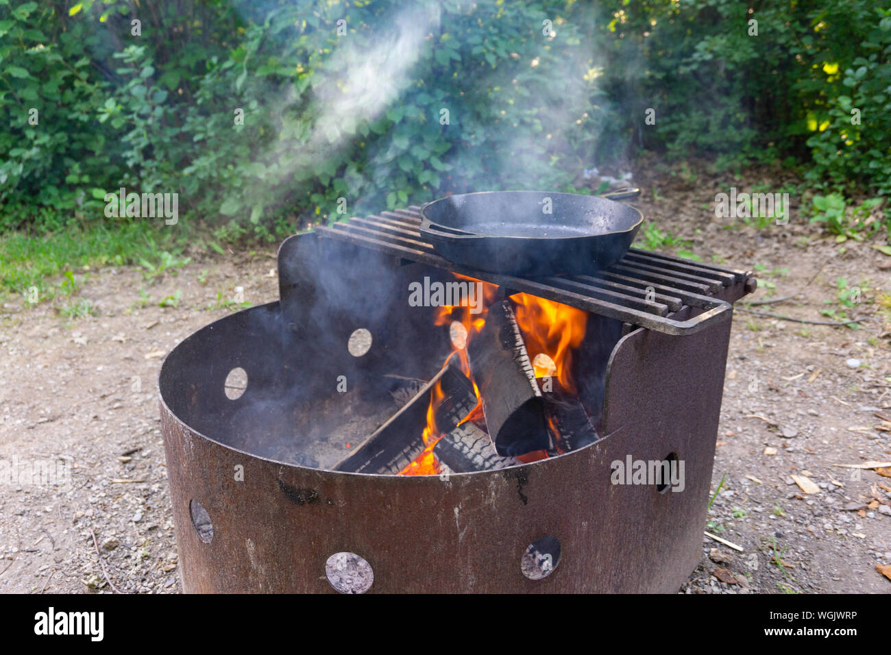 Cast iron skillet warming over bonfire camping cooking Stock Photo - Alamy
