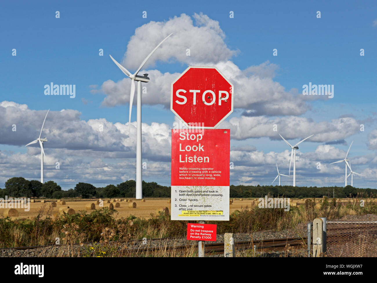 Sign at railway crossing - stop, look, listen - and wind turbines, near ...