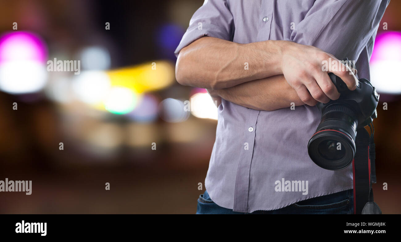 Young man holds black modern digital camera on natural background Stock ...
