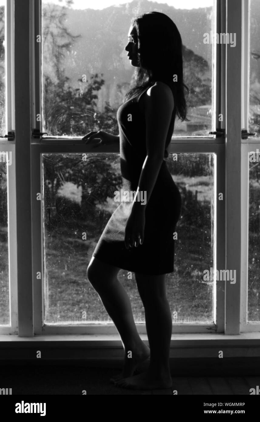Woman standing by full length window Black and White Stock Photos ...