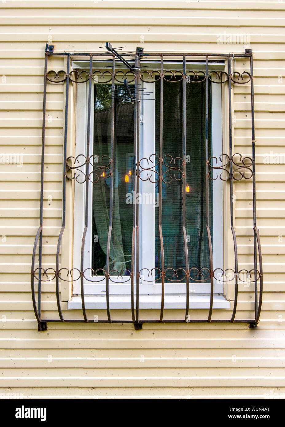 White plastic window with a beautiful forged lattice on it against the ...