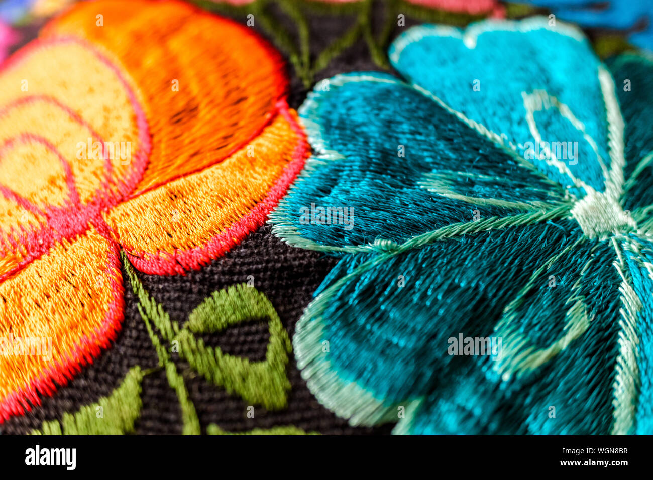 Background of hand-embroidered flowers on a fabric with colored threads ...