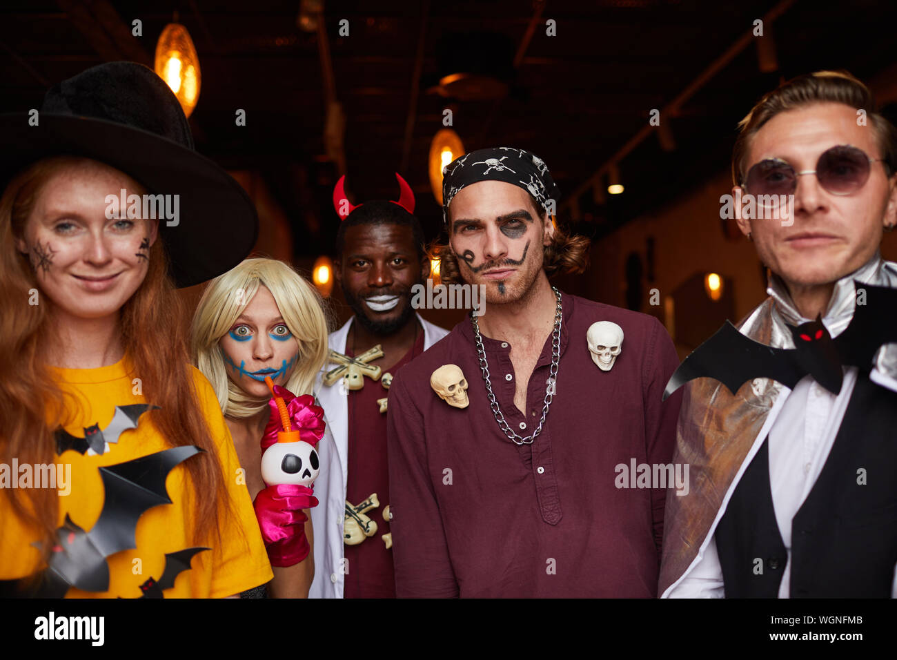 Multi-ethnic group of people wearing Halloween costumes posing looking ...