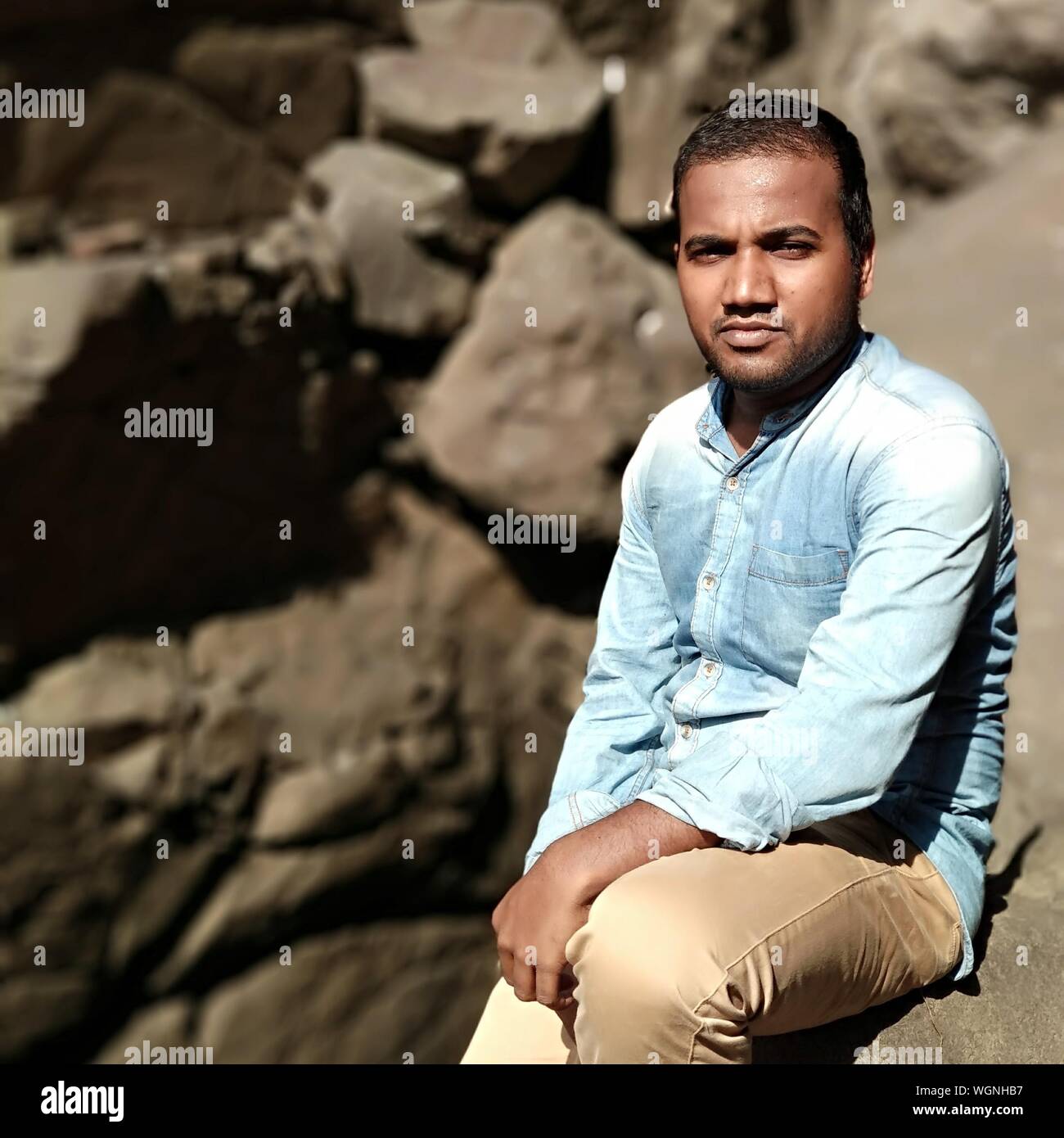 Young man sitting on rock hi-res stock photography and images - Alamy