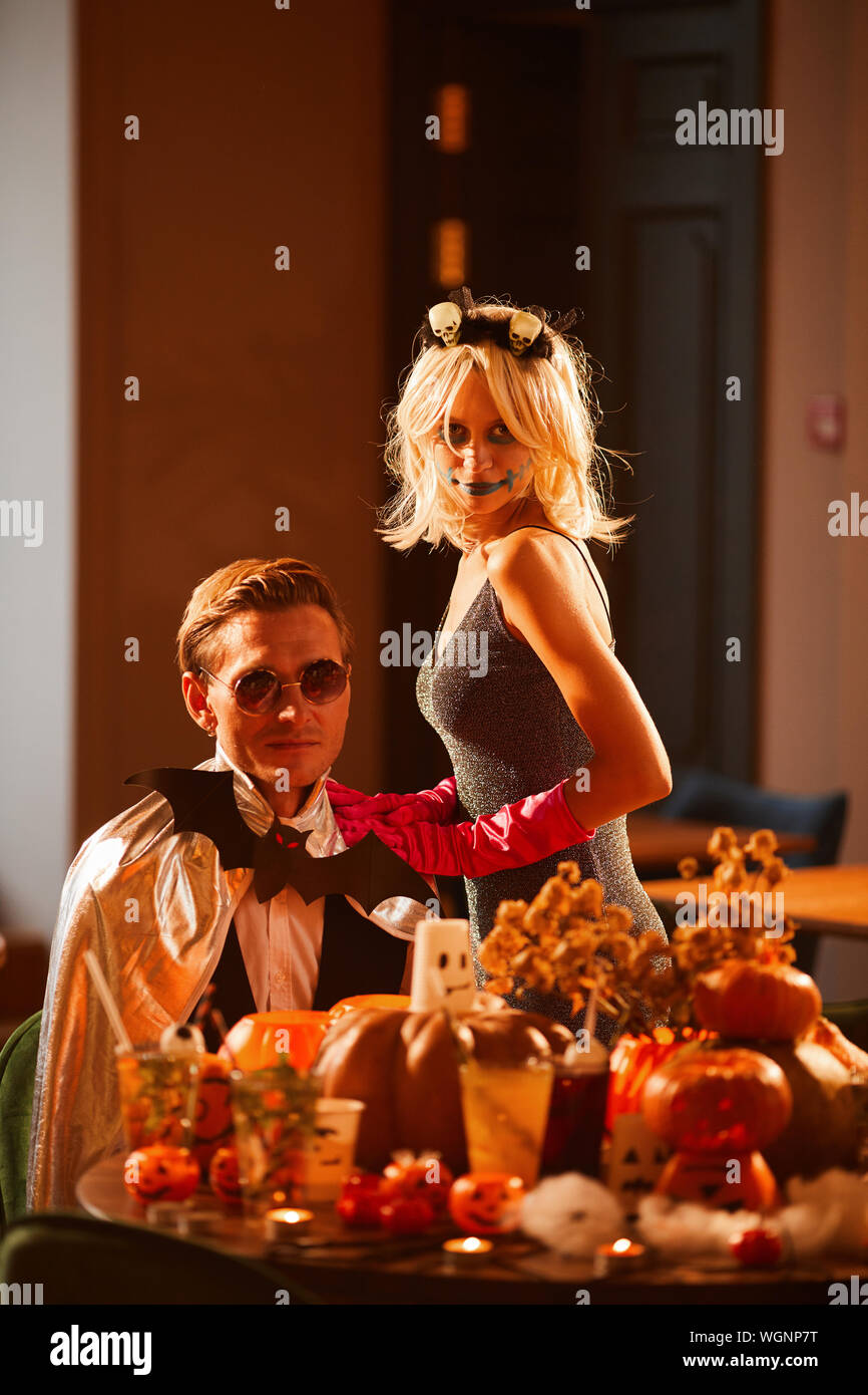 Portrait of adult couple wearing Halloween costumes posing by decorated ...