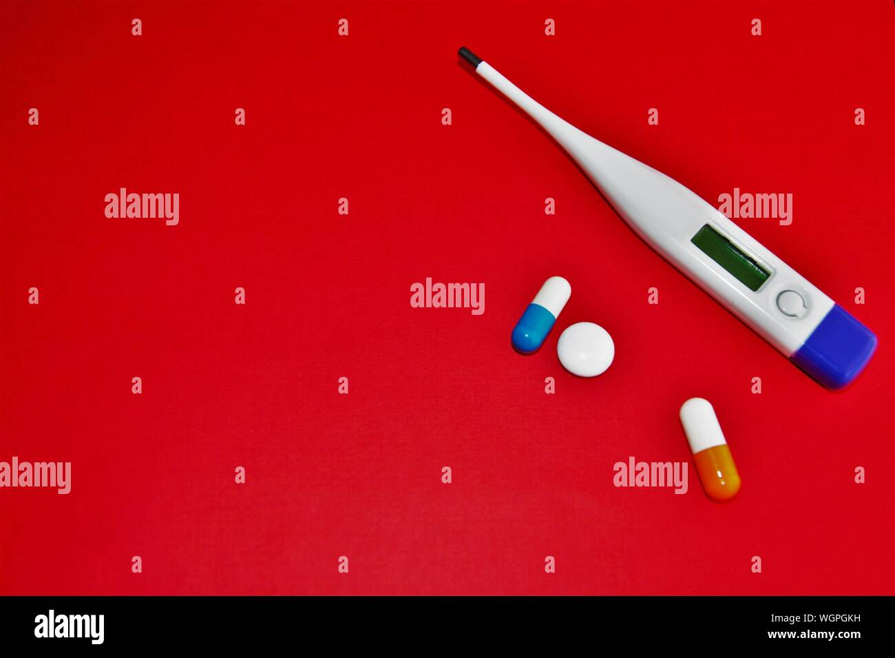 Spring flu, cold - pills and a thermometer on a red background - no ...