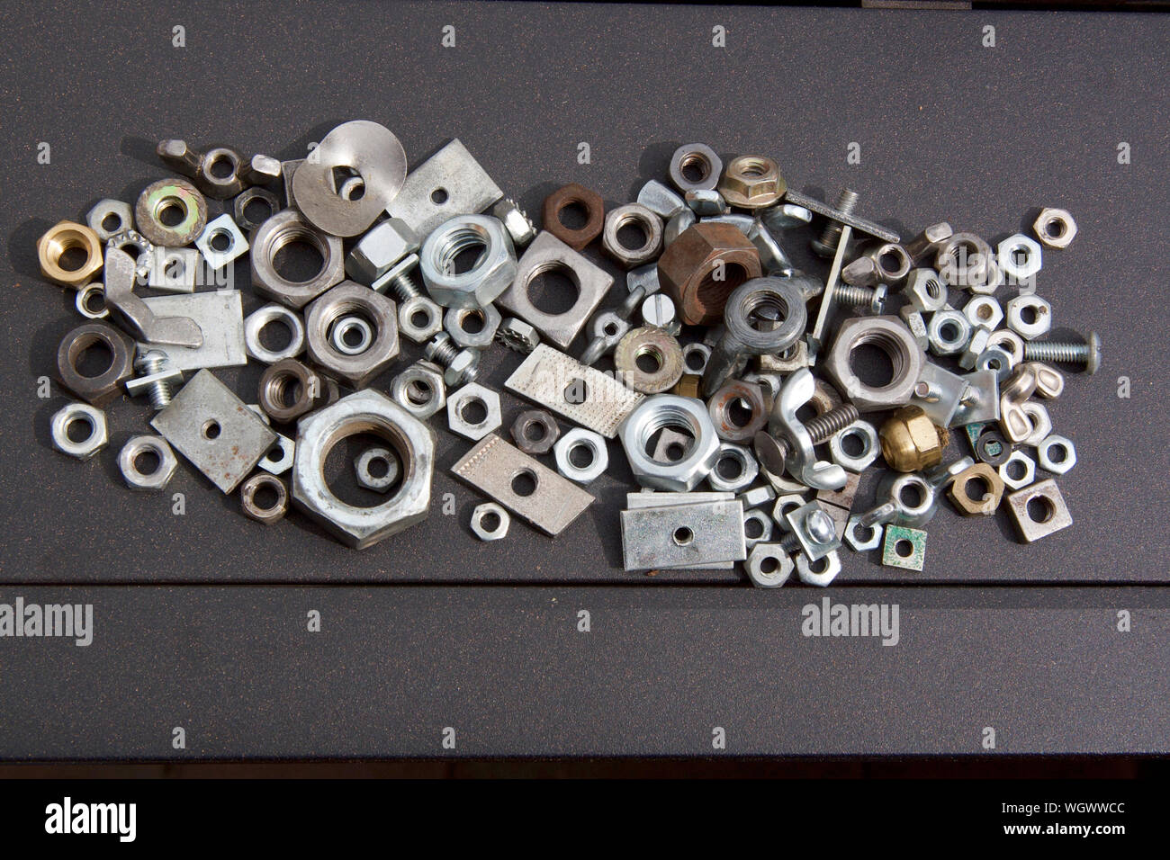 An odd assortment of metal nuts in different conditions with a mixture ...