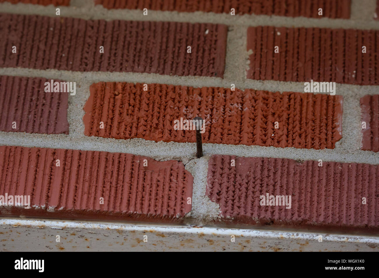 Large, rusty nail sticking out of a red brick wall Stock Photo - Alamy