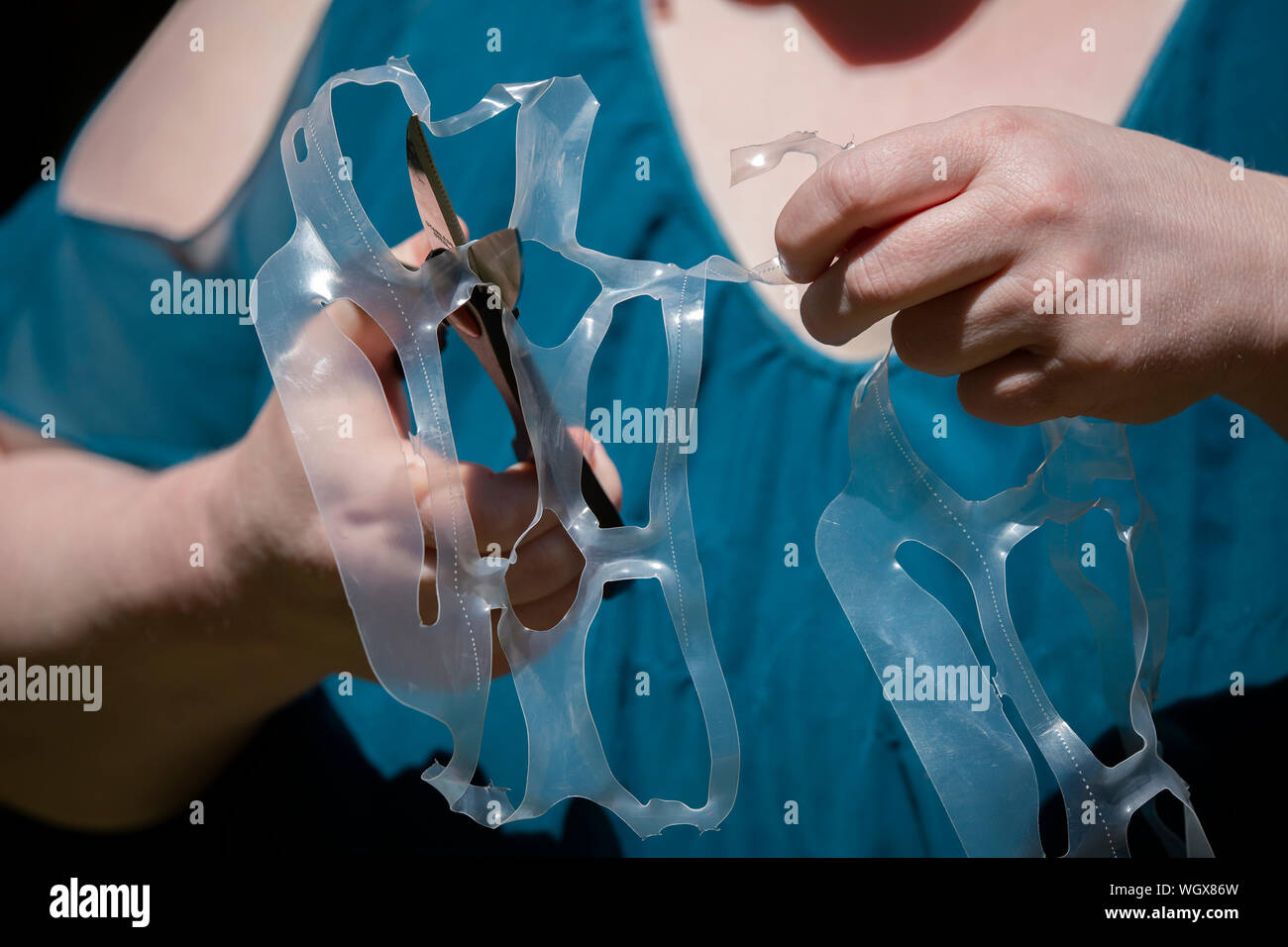 Woman cutting plastic rings before throwing them away to prevent them ...