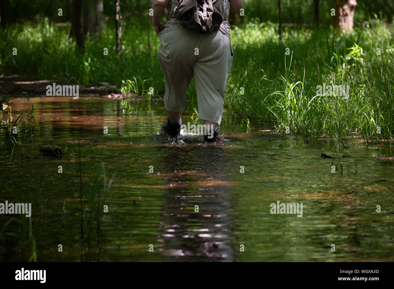 Legs and boots of a woman walking through ankle-deep water in nature ...