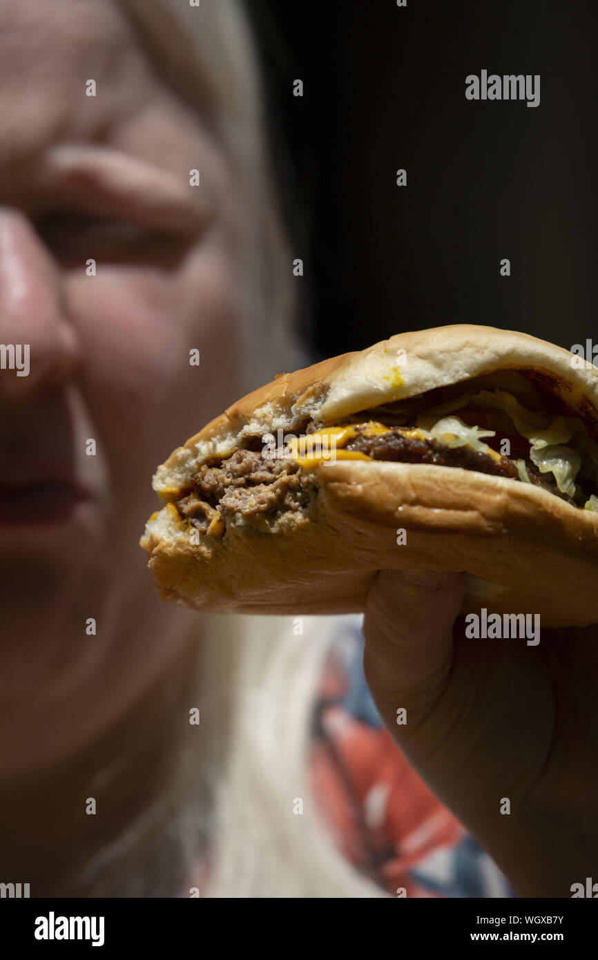 Albino woman eating a double meat cheese burger Stock Photo - Alamy
