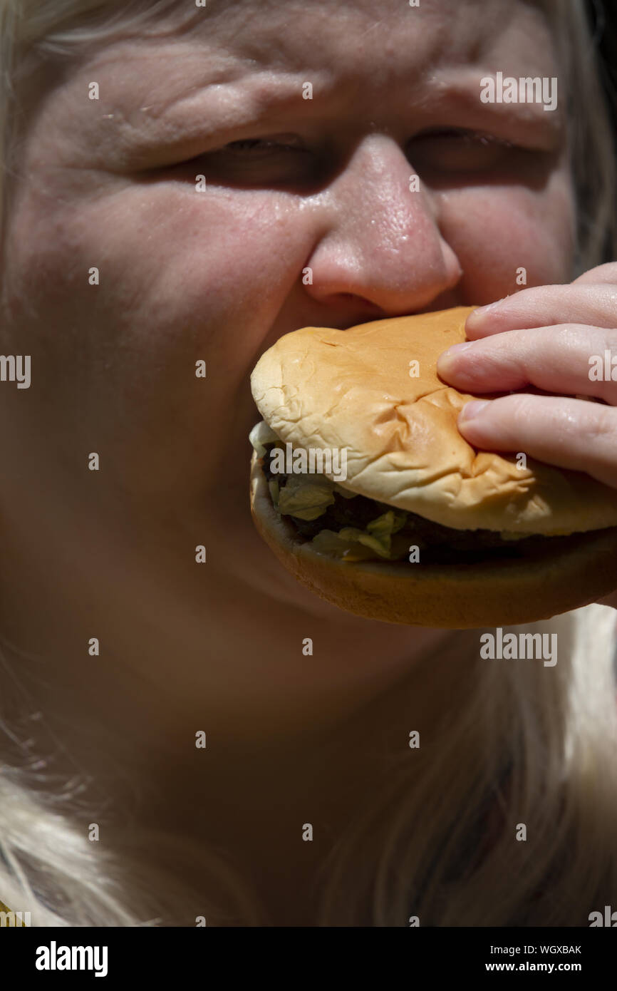 Albino woman eating a double meat cheese burger Stock Photo - Alamy