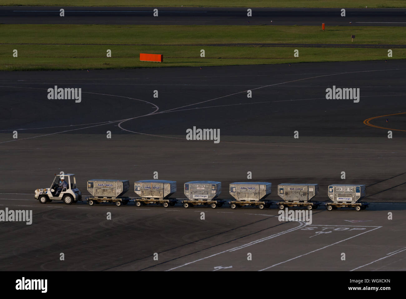 A small tractor car (called a tug) towing cargo containers for ...