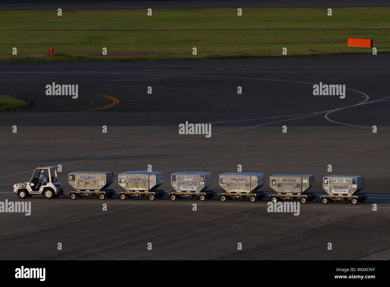 A small tractor car (called a tug) towing cargo containers for ...