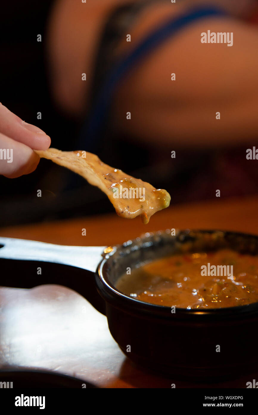 Man dipping a chip into spicy queso dip Stock Photo - Alamy