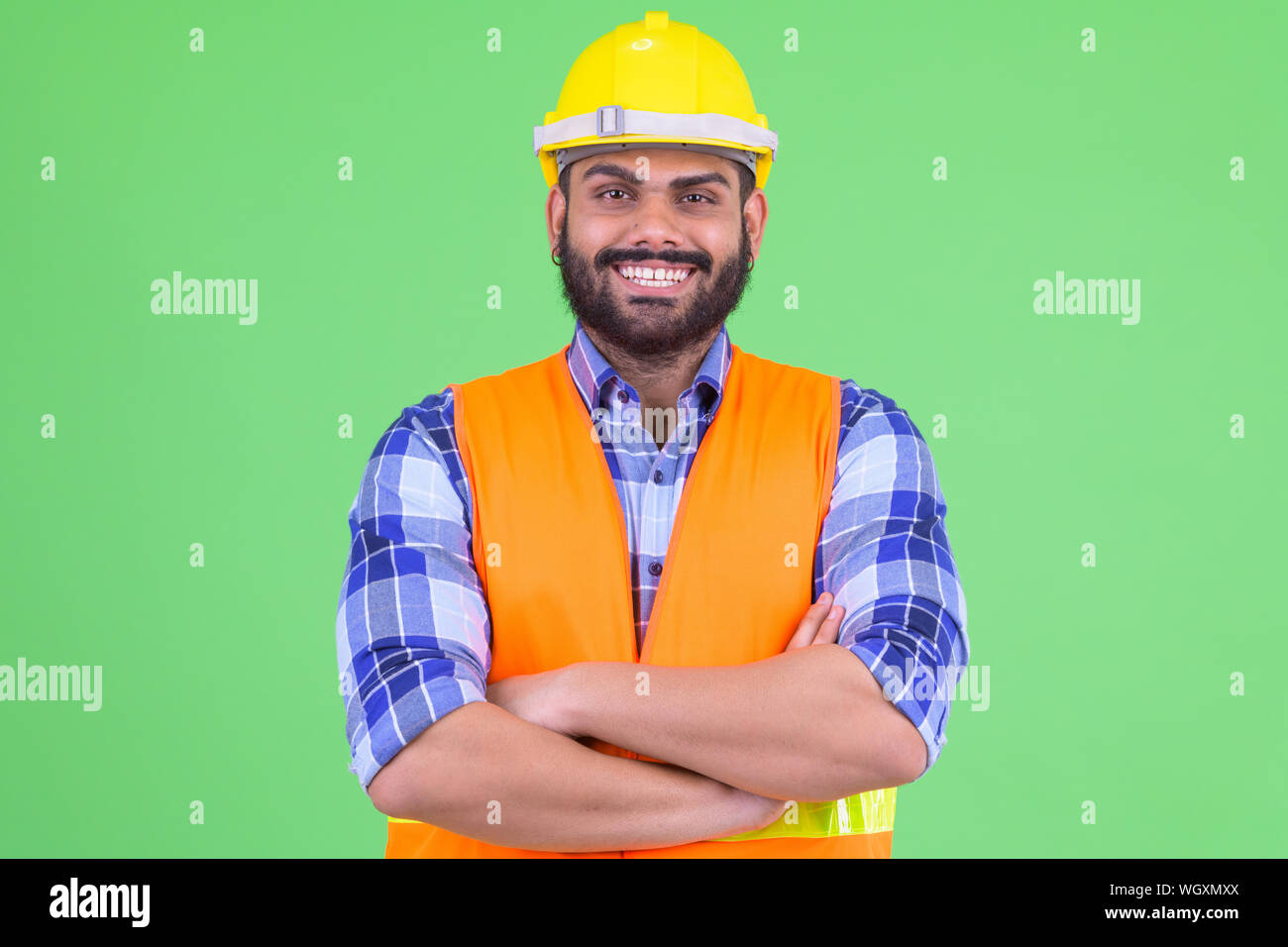 Happy young overweight bearded Indian man construction worker smiling ...