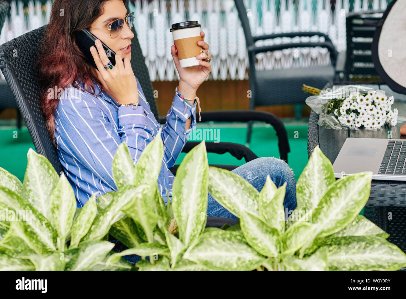 Beautiful young woman leaning back in chair, drinking cup of take away ...