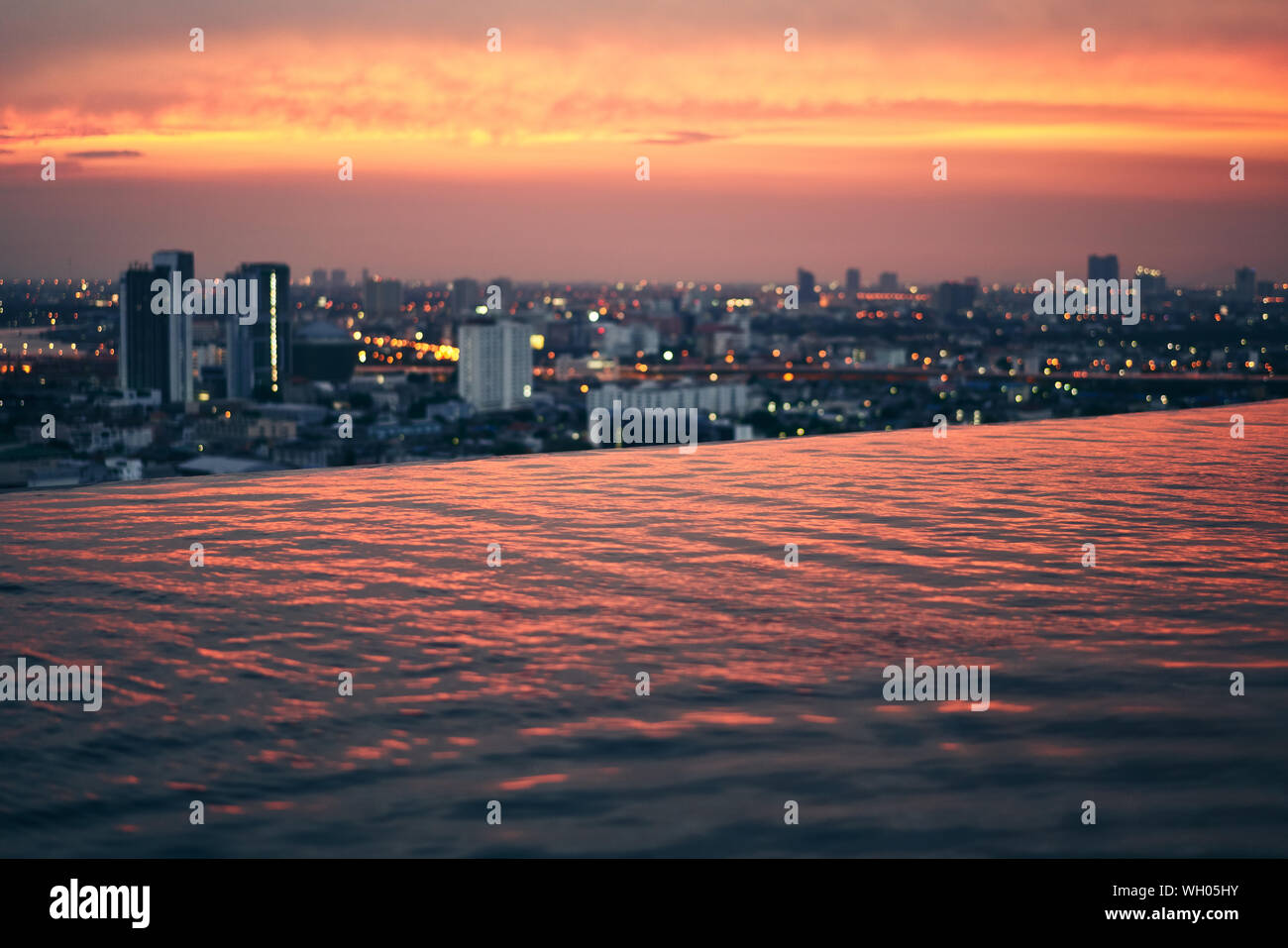 Amazing colorful sunset in big city. Roof top view with swimming pool ...