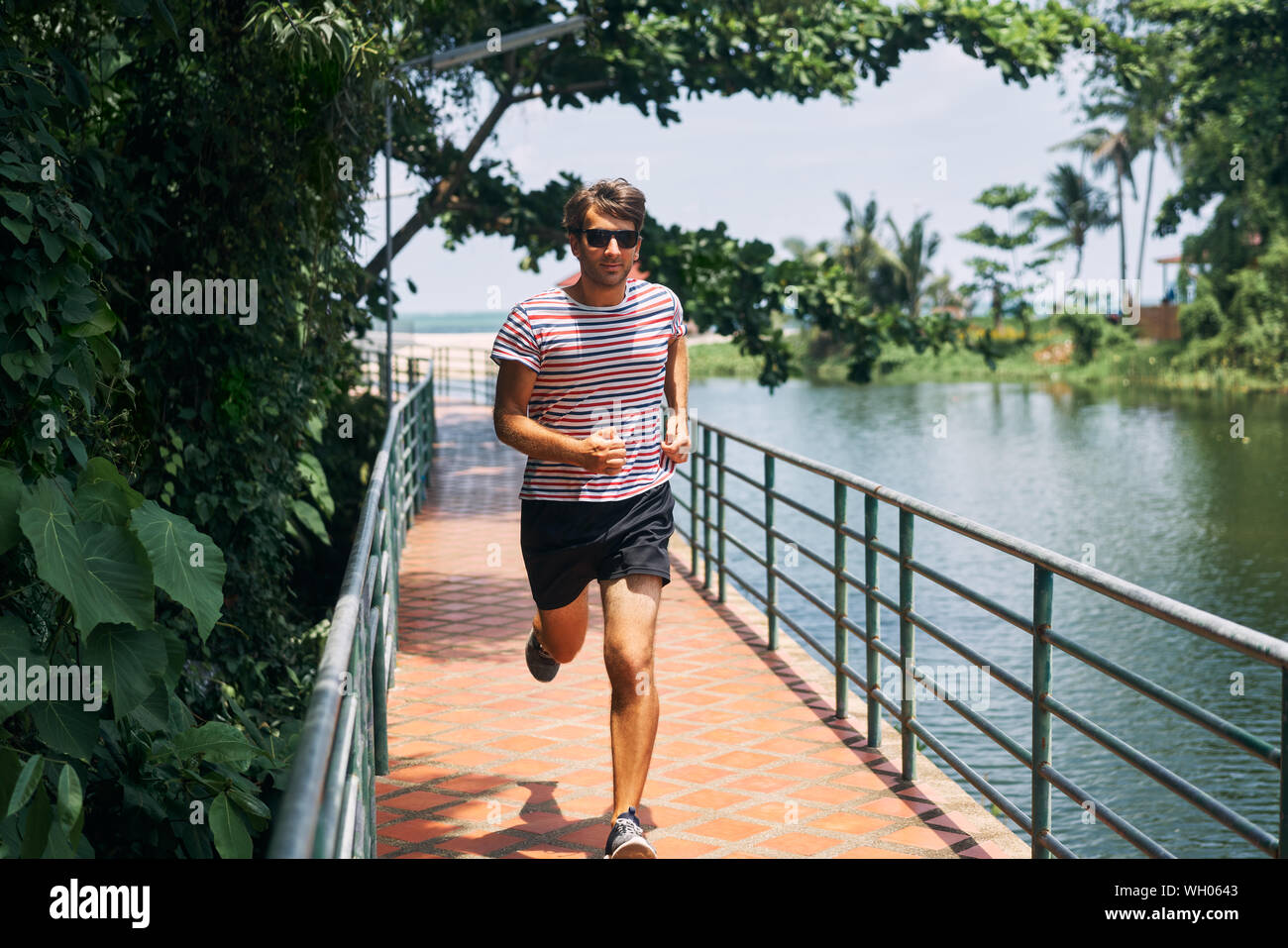 Full length shot of healthy young man running on the bridge. Fitness ...
