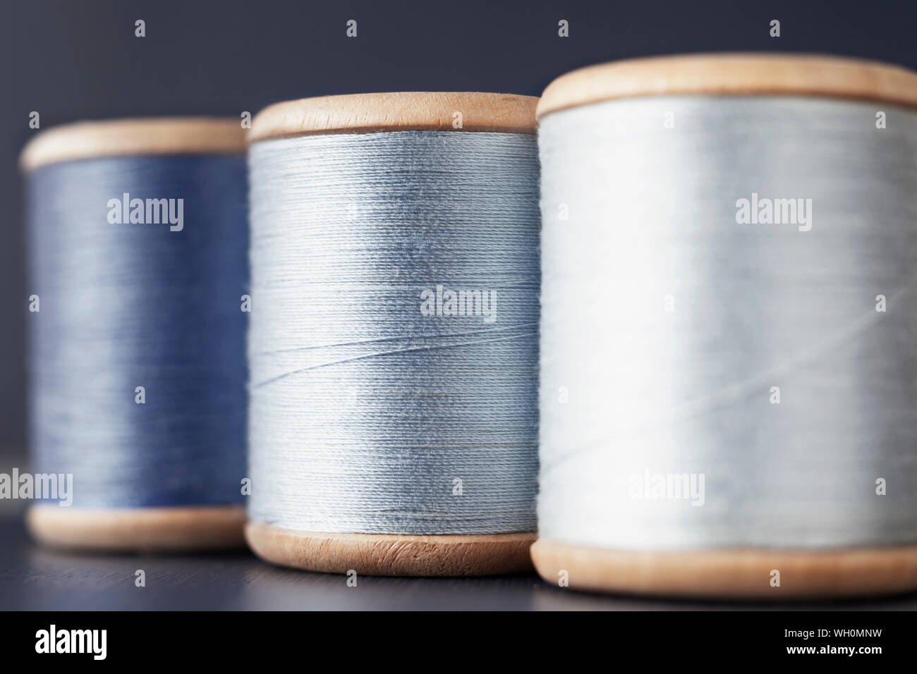 Three wooden spools of colored thread on colored background , different ...