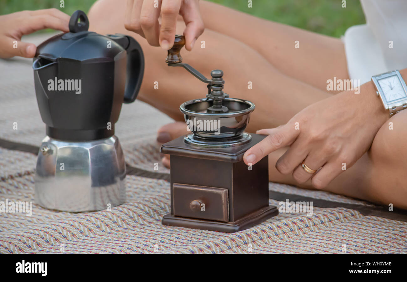 Hand rotating grinding coffee beans and the coffee pot is placed on the ...