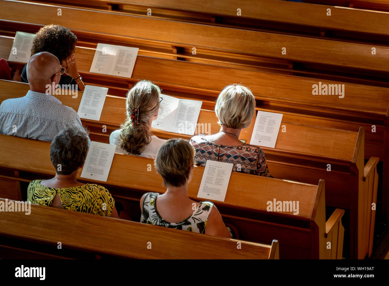 People in wooden benches in dutch church reading the holy literugie and ...