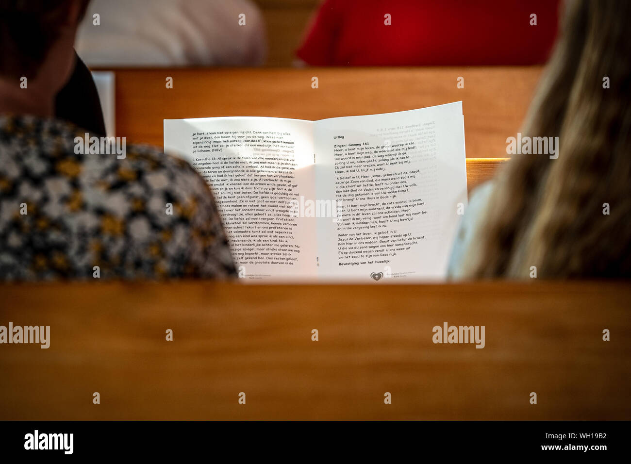 People in wooden benches in dutch church reading the holy literugie and ...