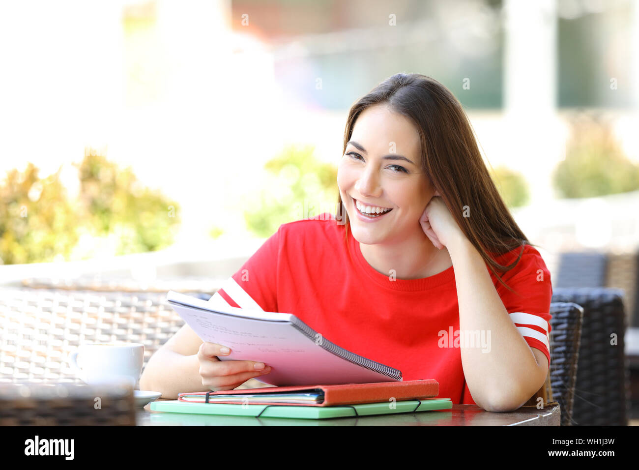 Happy student looking at camera sitting in a coffee shop terrace Stock ...