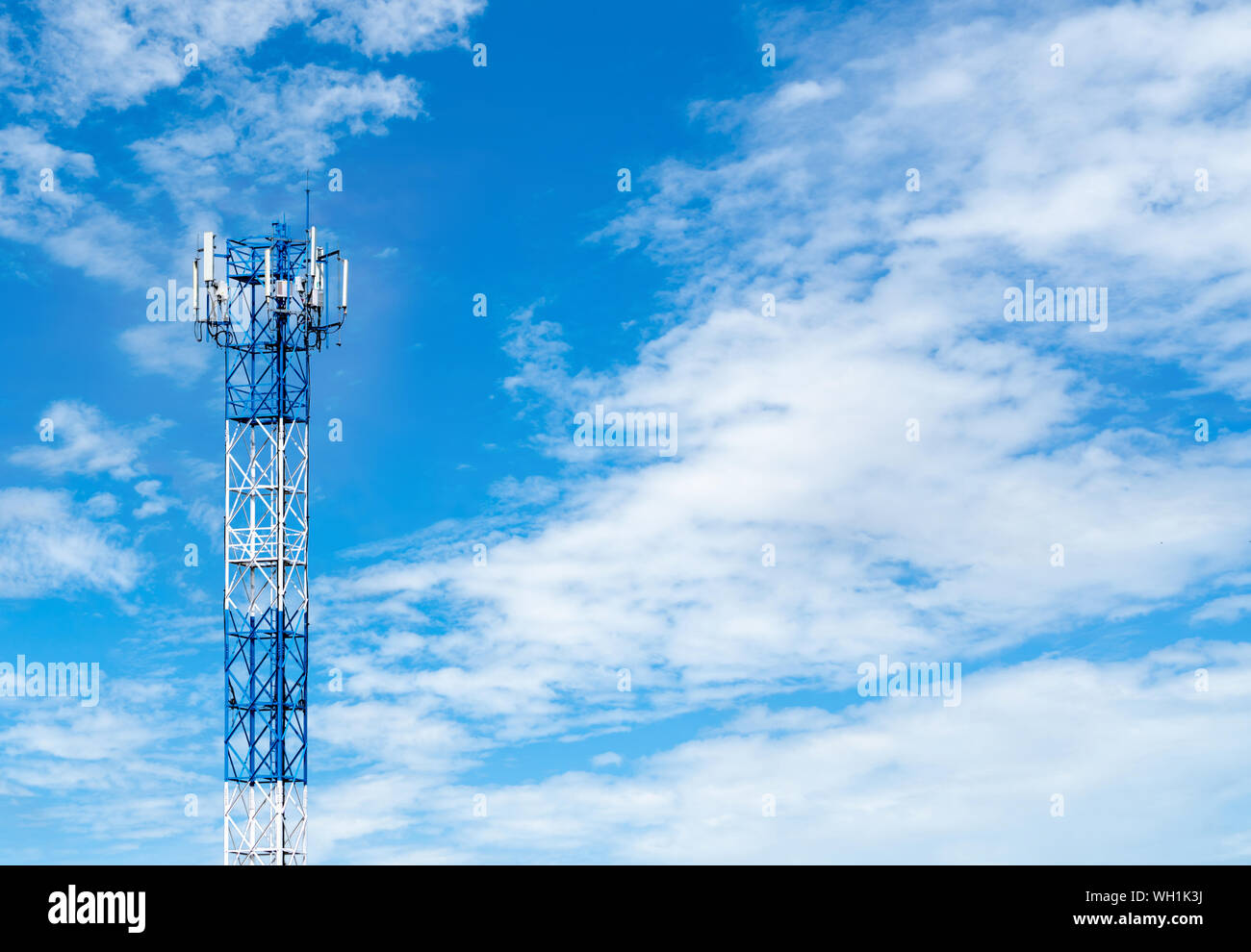 Telecommunication tower with blue sky and white clouds background. Antenna on blue sky. Radio ...