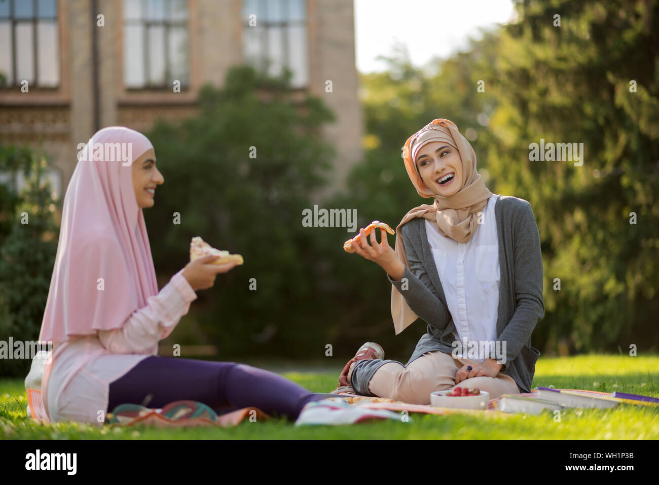 Muslim students laughing and eating pizza enjoying lunch break Stock ...