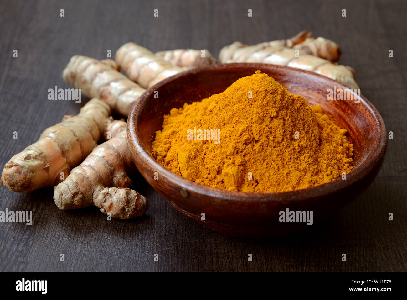 Fresh turmeric powder in a bowl and turmeric root, Indian spices an ...