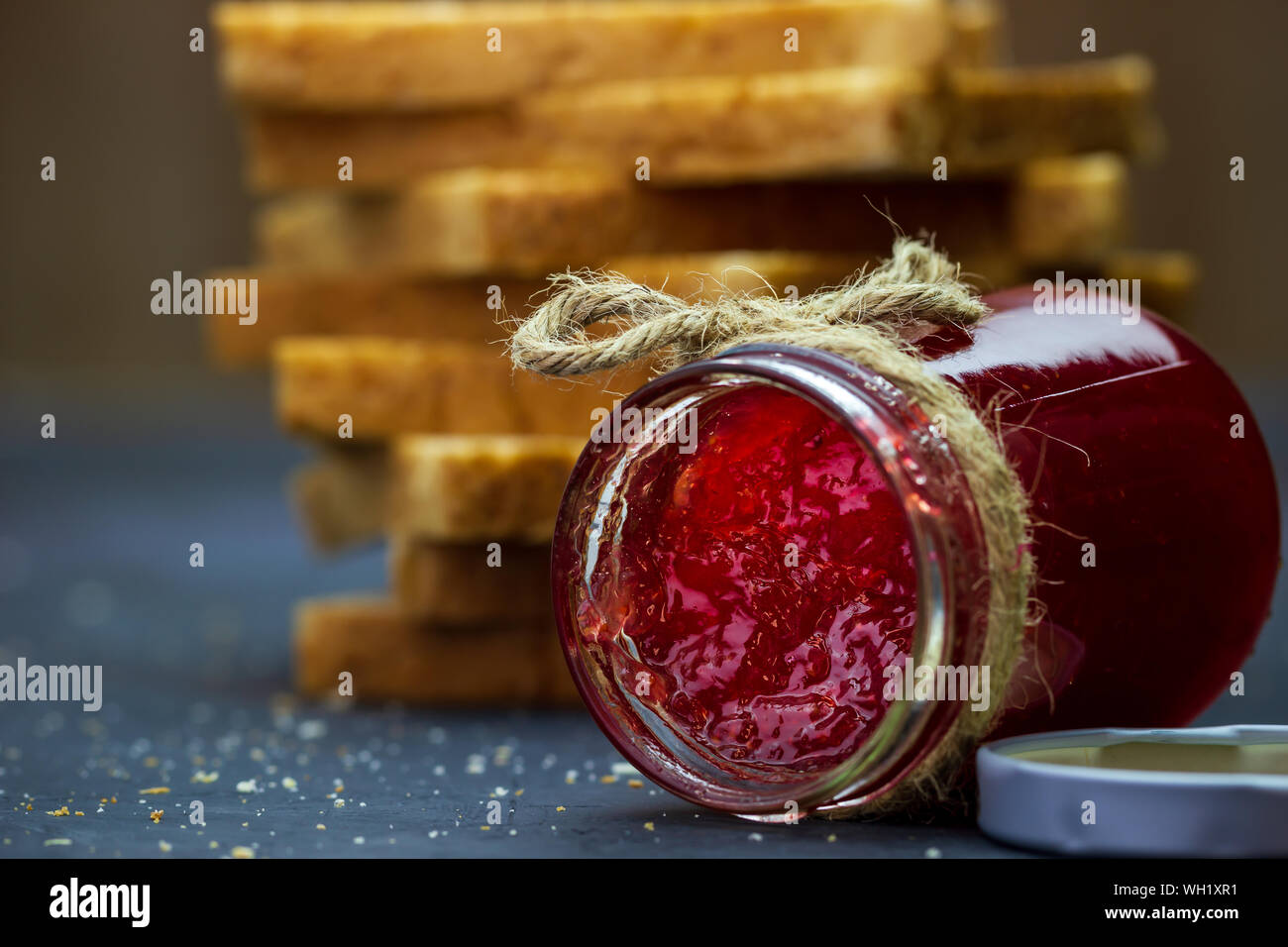 Strawberry jam bottle and whole wheat bread are stacked on a black ...