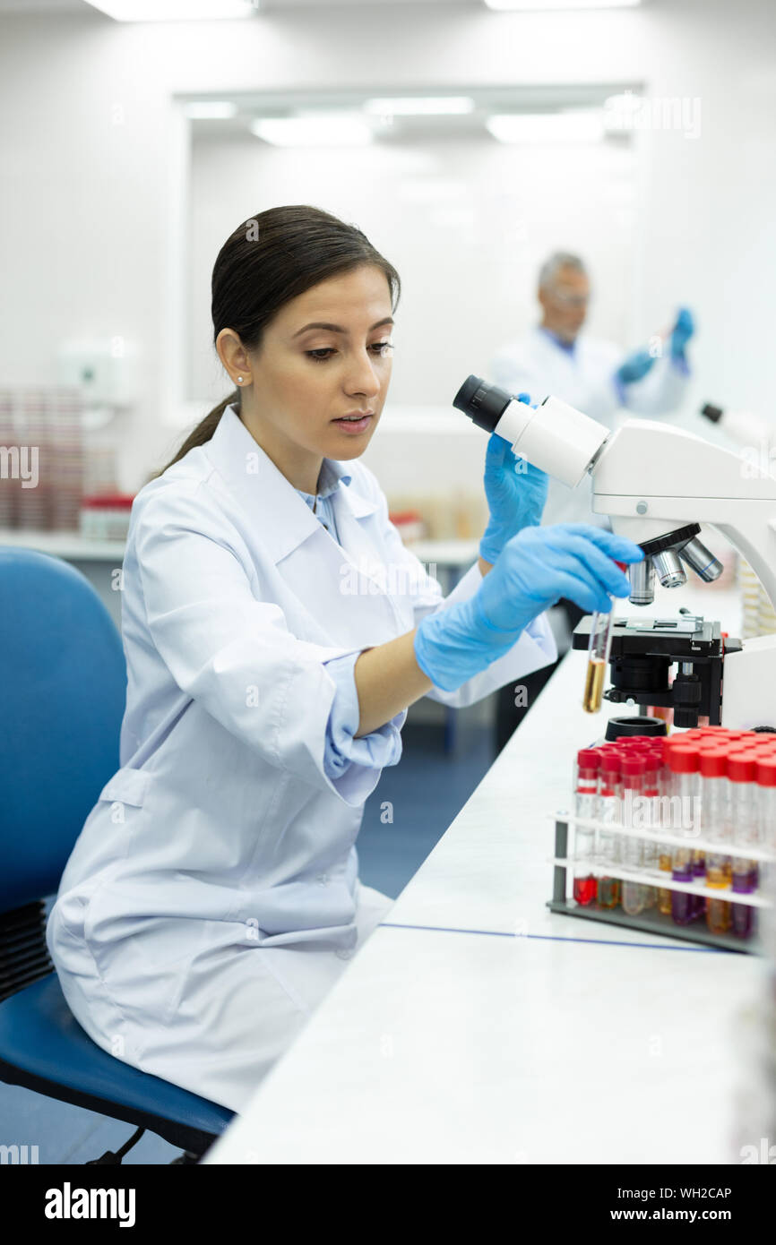 Pretty young chemist looking at test tube Stock Photo - Alamy