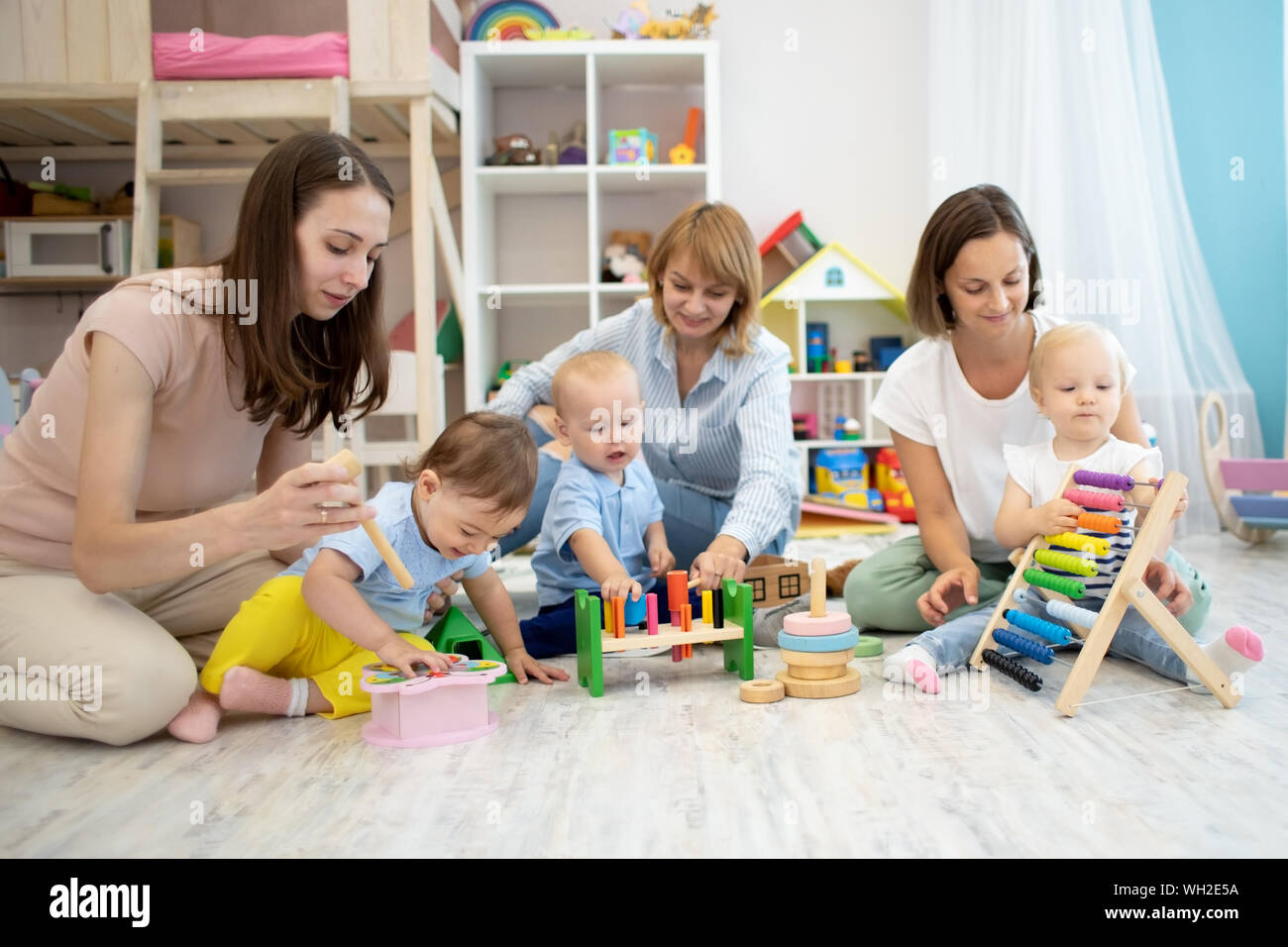 Mothers with their babies play with developmental toys in daycare ...