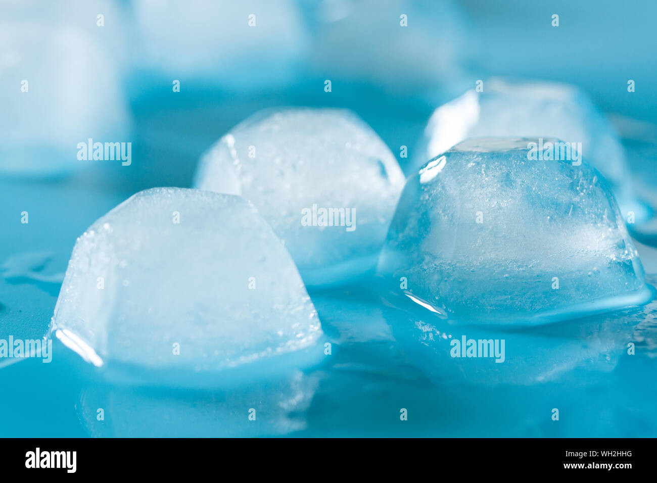 Melting ice cubes background on blue background Stock Photo - Alamy