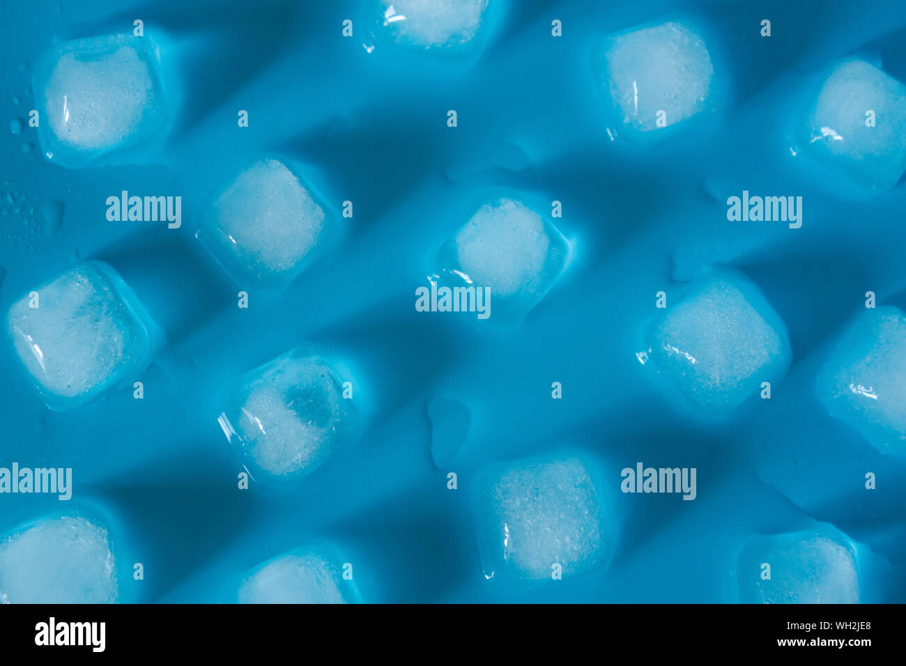 Melting ice cubes background on blue background Stock Photo - Alamy