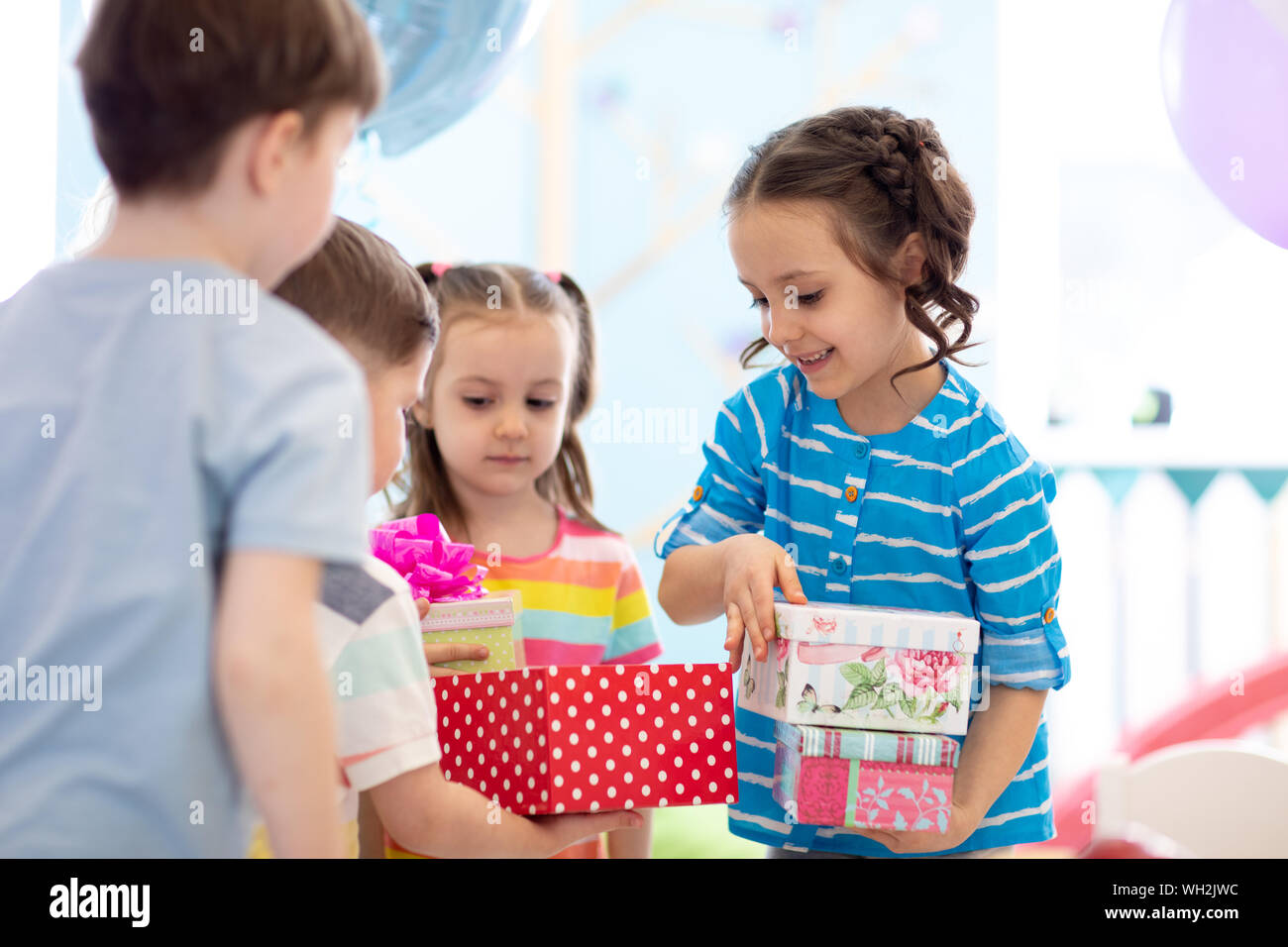 Joyful little child kid girl receiving gifts at birthday party ...
