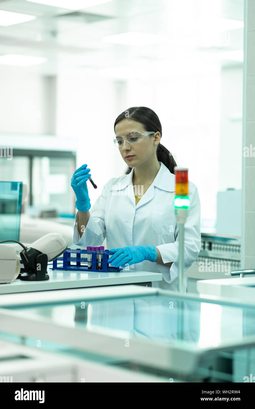 Concentrated young medical worker looking at test tube Stock Photo - Alamy