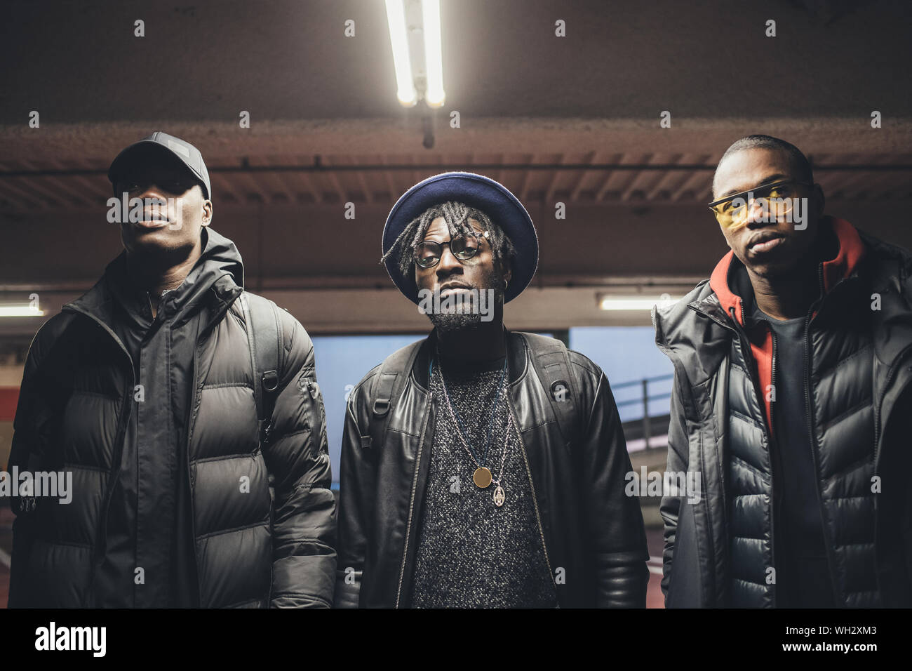 portrait three young black men posing in a parking lot looking away ...