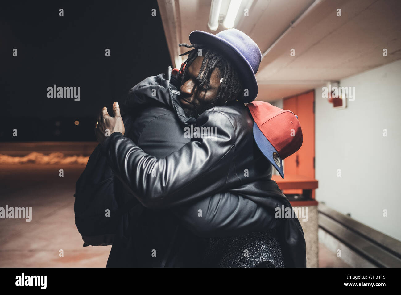 two young african men outdoor together in the street hugging having fun ...
