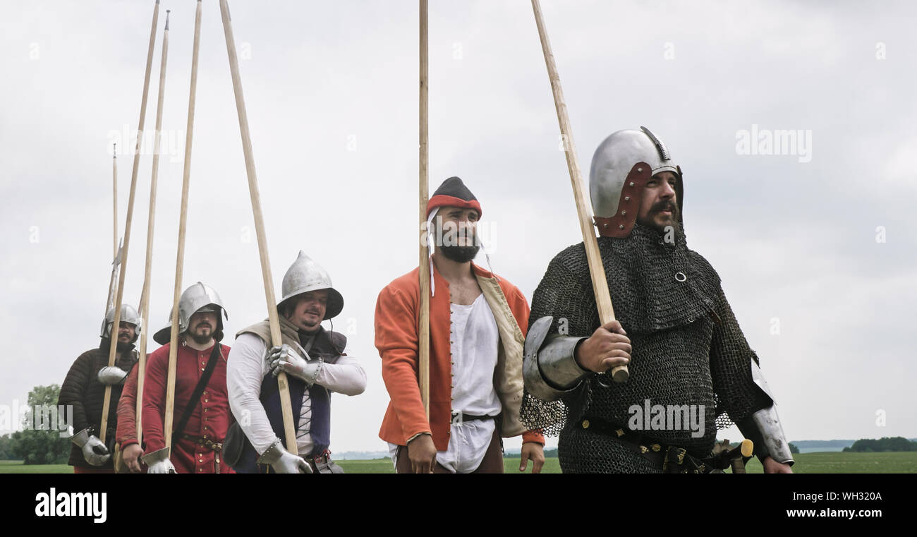 Group of medieval knights with a spears and helmets on the heads going ...