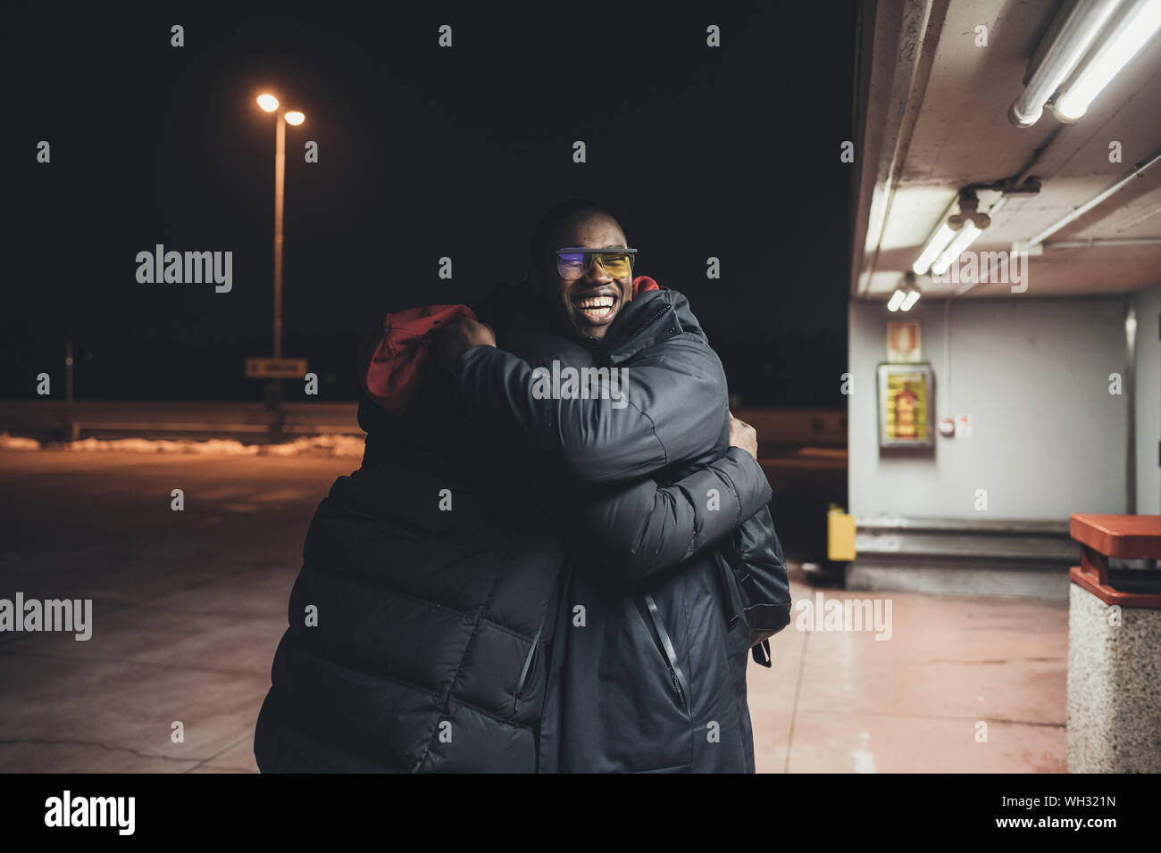 two young african men outdoor together in the street hugging having fun ...