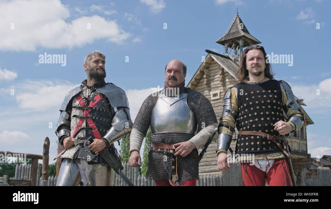 Medieval knights going on camera against wooden fortress background ...