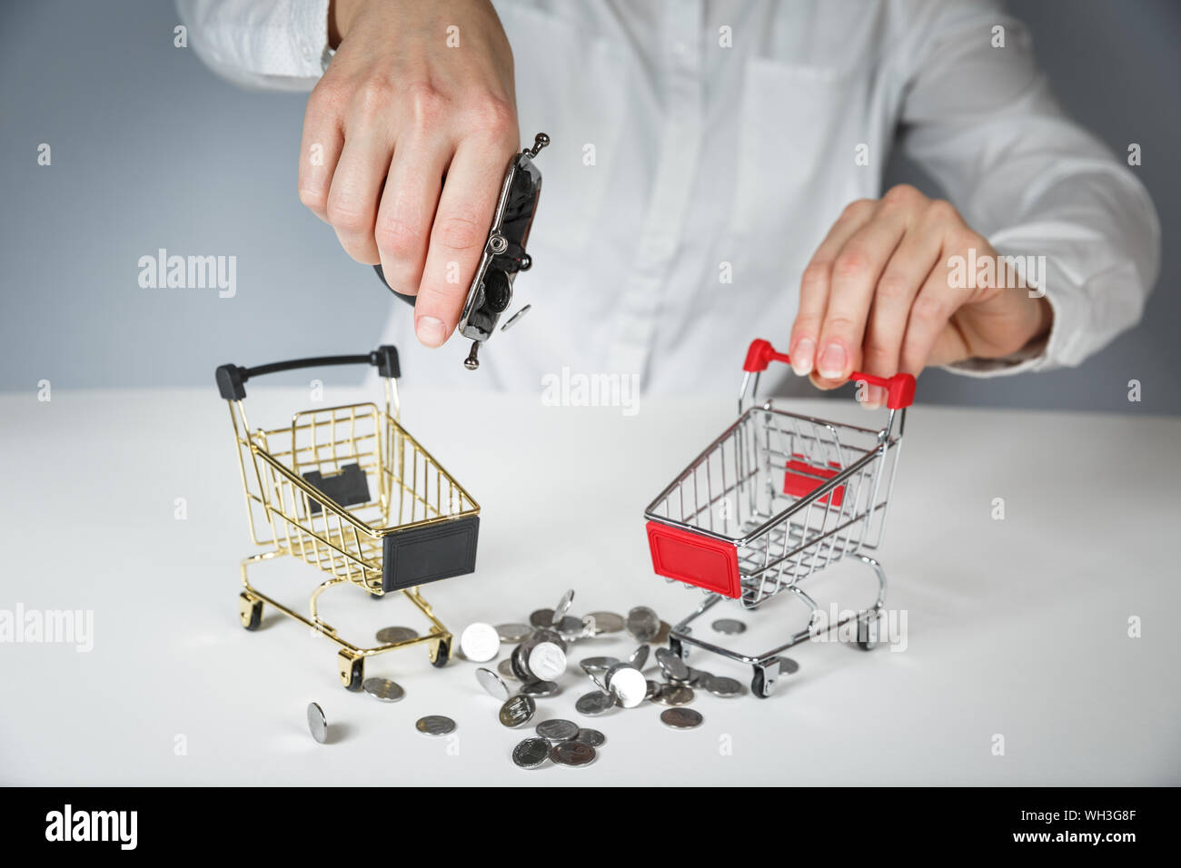 Hand holding a coin with pile of coin in the shopping cart on white and ...