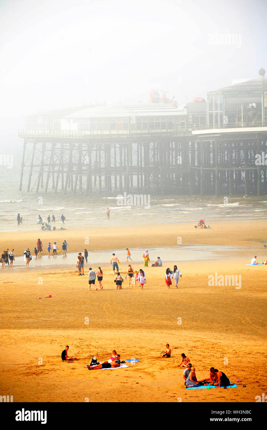 Blackpool beach and North Pier on a hot and misty August bank holiday ...