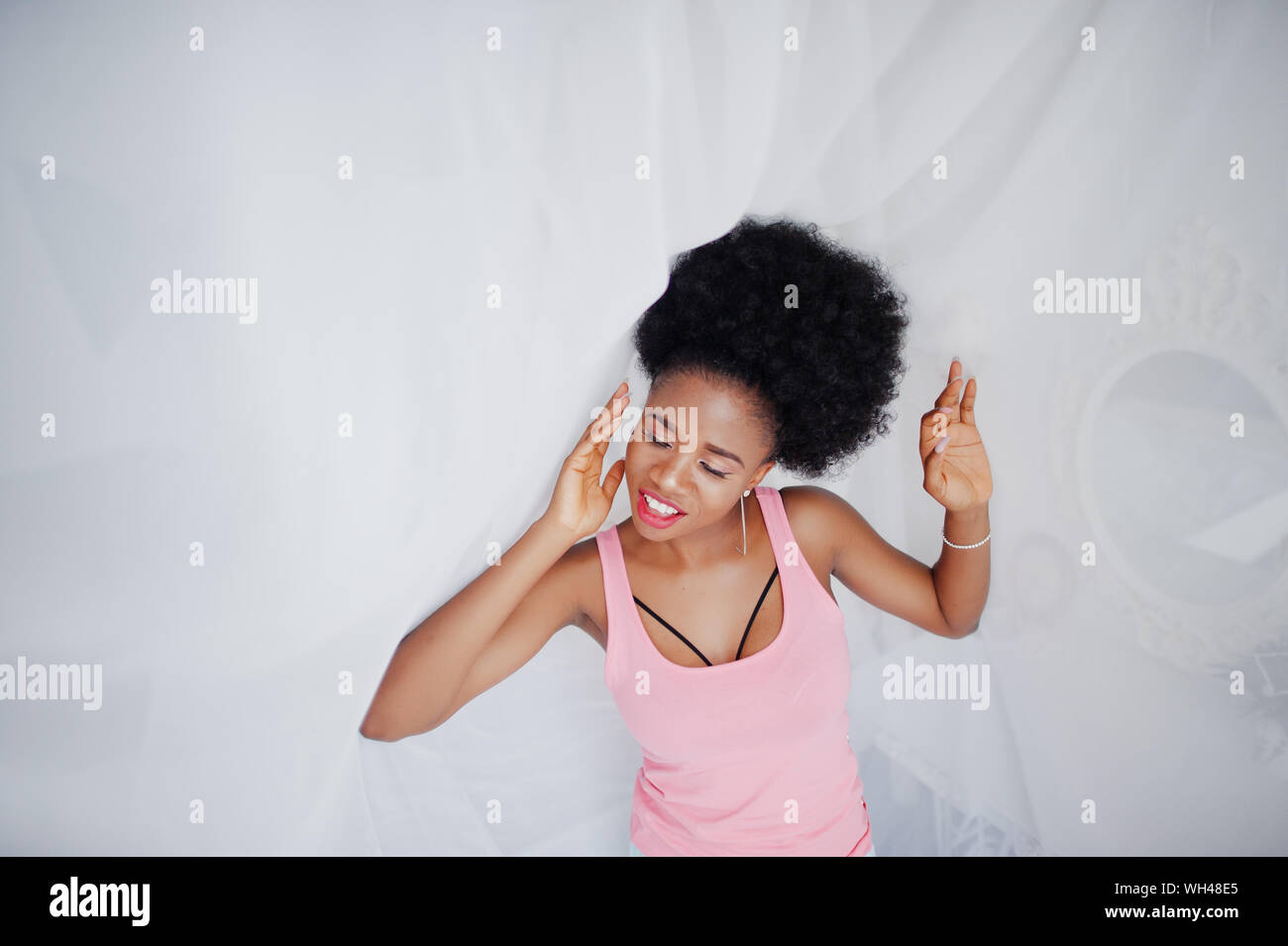 Young african american woman in pink singlet against window touching ...