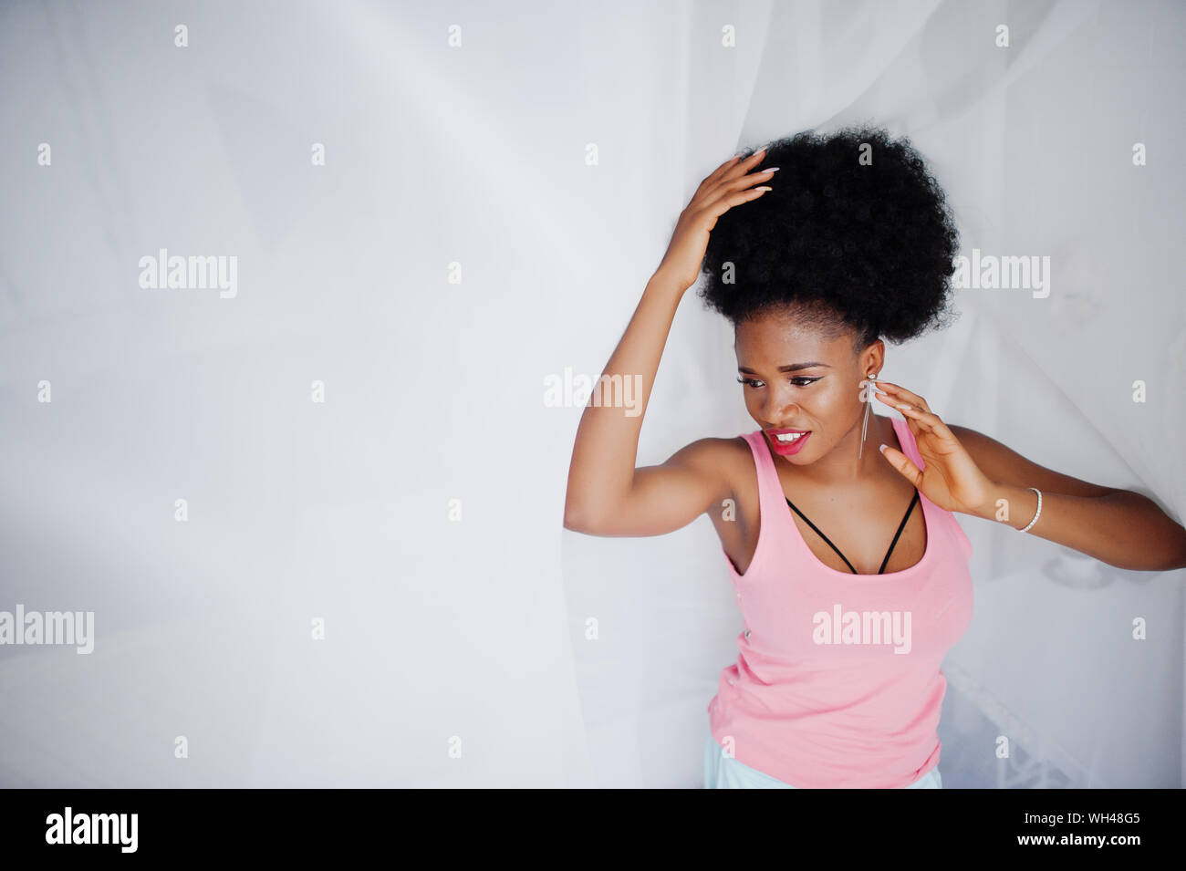 Young african american woman in pink singlet against window touching ...