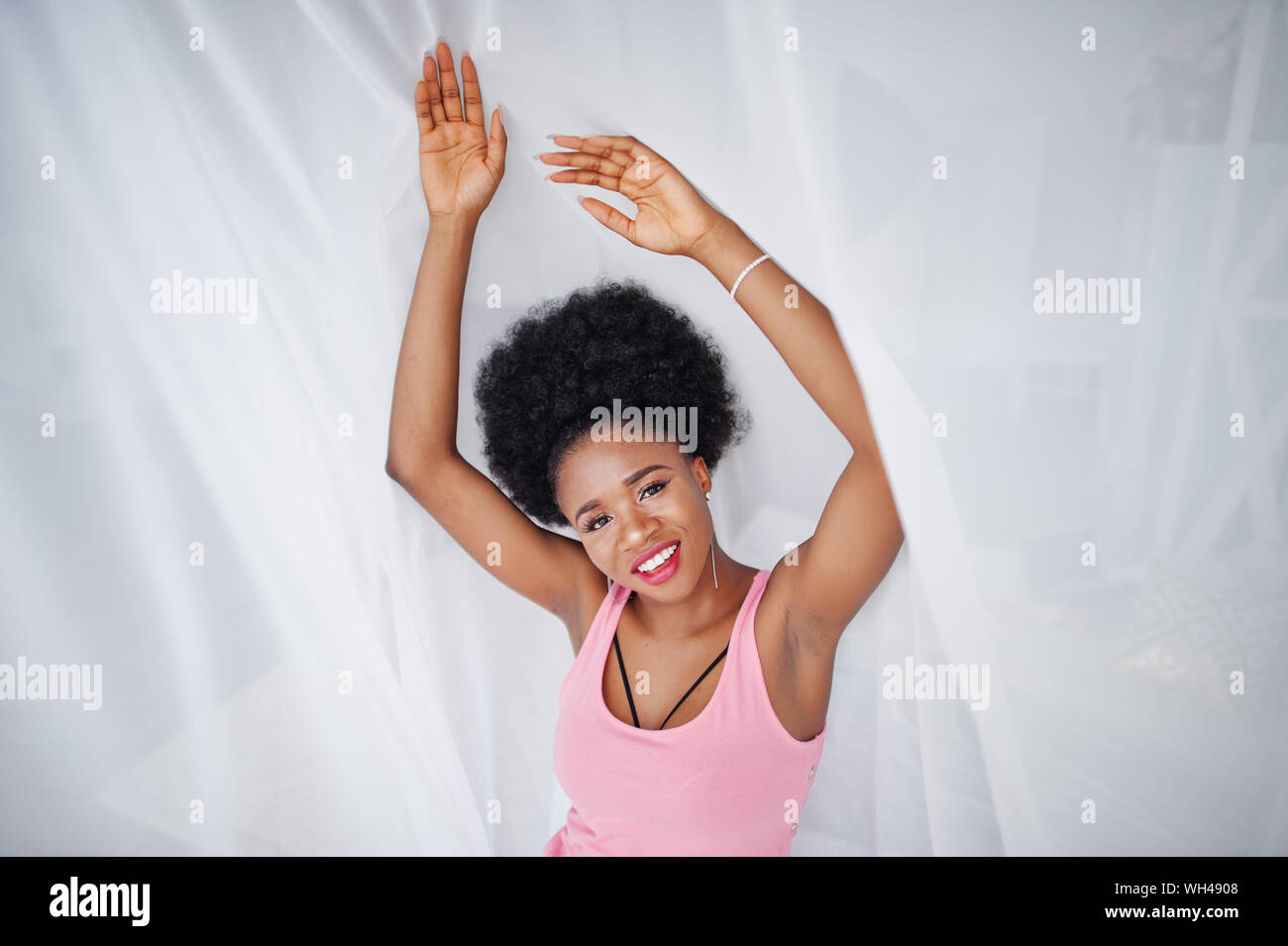 Young african american woman in pink singlet against window touching ...