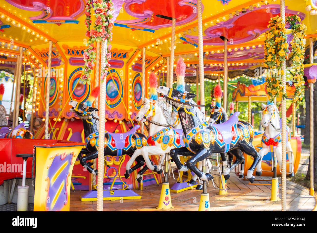 Old French carousel in a holiday park. Three horses on a traditional ...