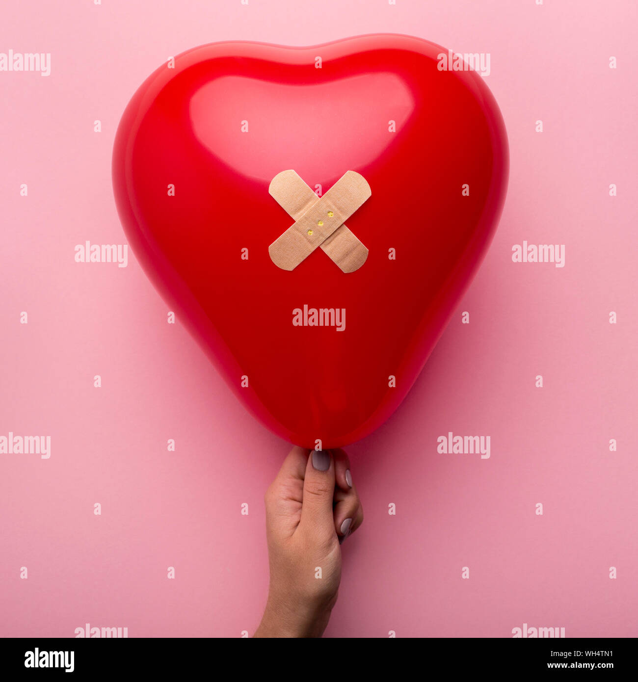 First aid with patch to wounded heart in woman hand on pink Stock Photo ...